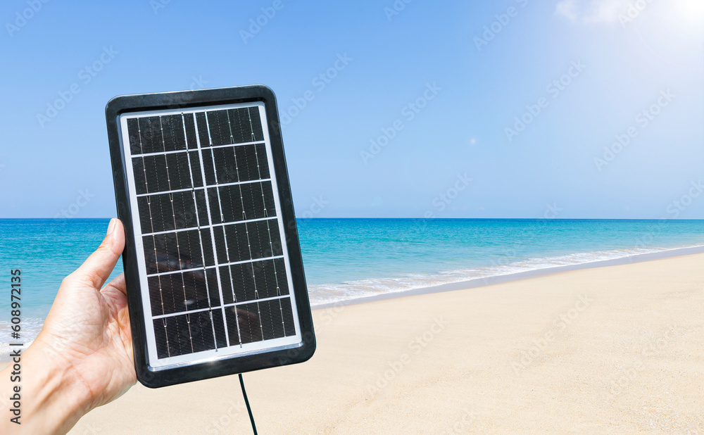 Portable solar cell panel in girl hand over beautiful beach background ...