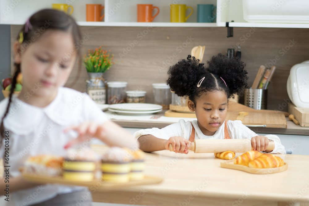 Two little girls in the kitchen prepare food, a dessert for the family ...