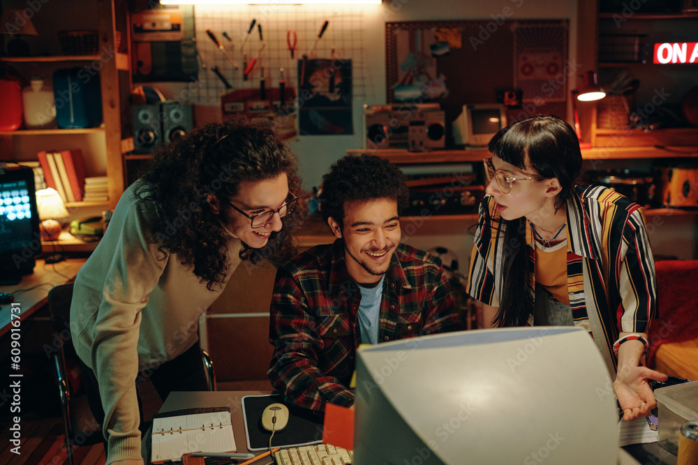 Group of young people looking at monitor of computer and discussing new ...