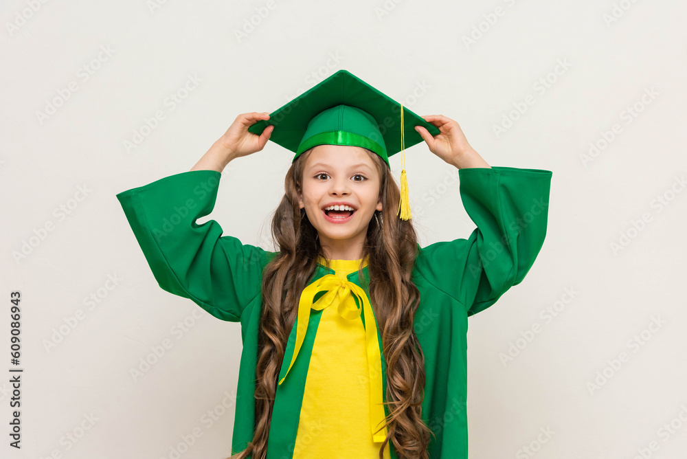 A little girl in a graduate costume for graduation. The schoolgirl is ...