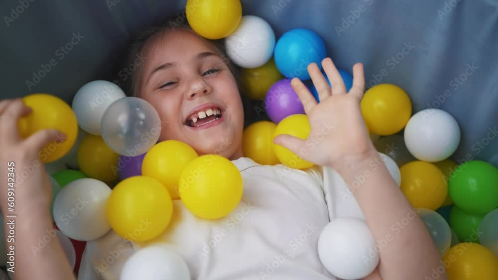 a child play in a dry pool with colored balls. happy family kid dream ...