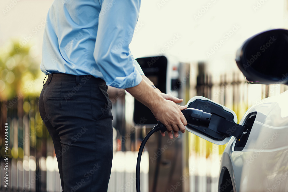 Closeup progressive man holding EV charger plug from public charging ...