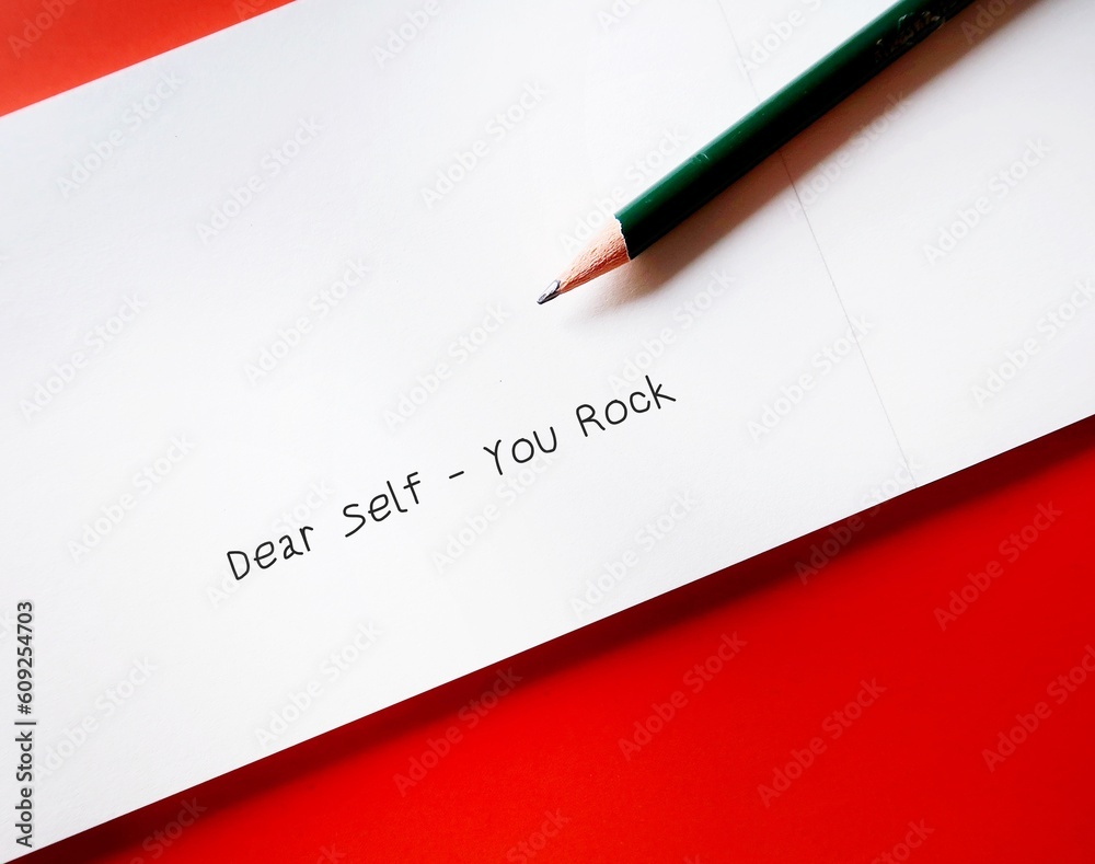 Notebook on orange background with handwritten text DEAR SELF YOU ROCK ...