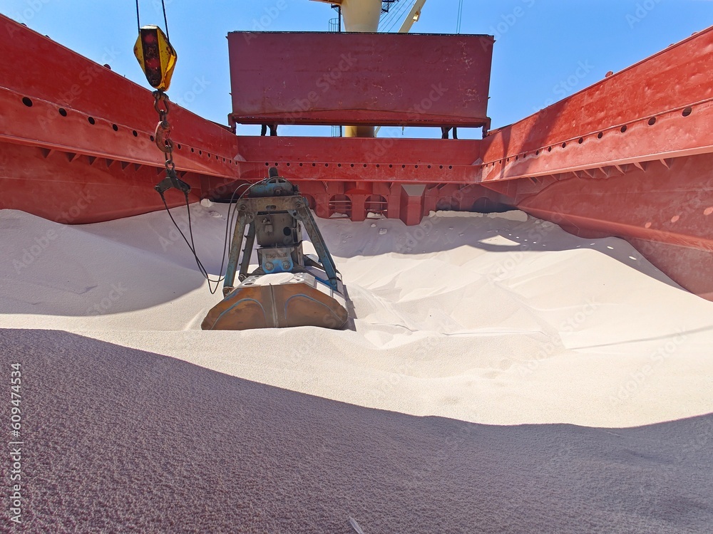 A grab is grabbing cargo in the hold of cargo ship or a bulk carrier ...