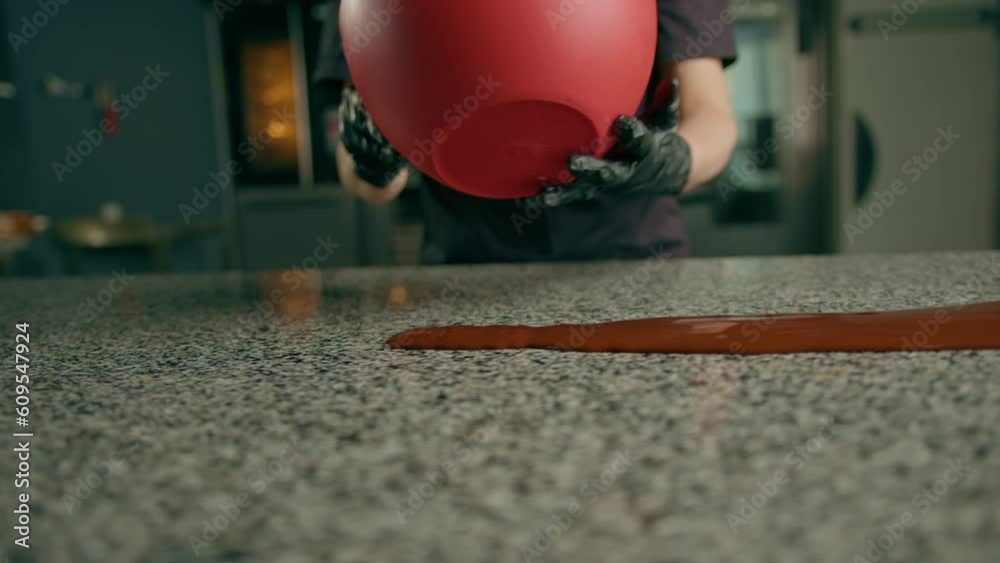 Pastry chef pours melted chocolate on stone table for tempering ...