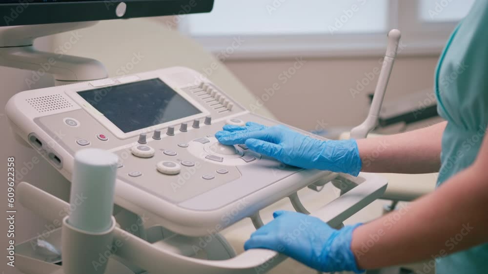 A gynecologist uses a transvaginal ultrasound device presses buttons ...