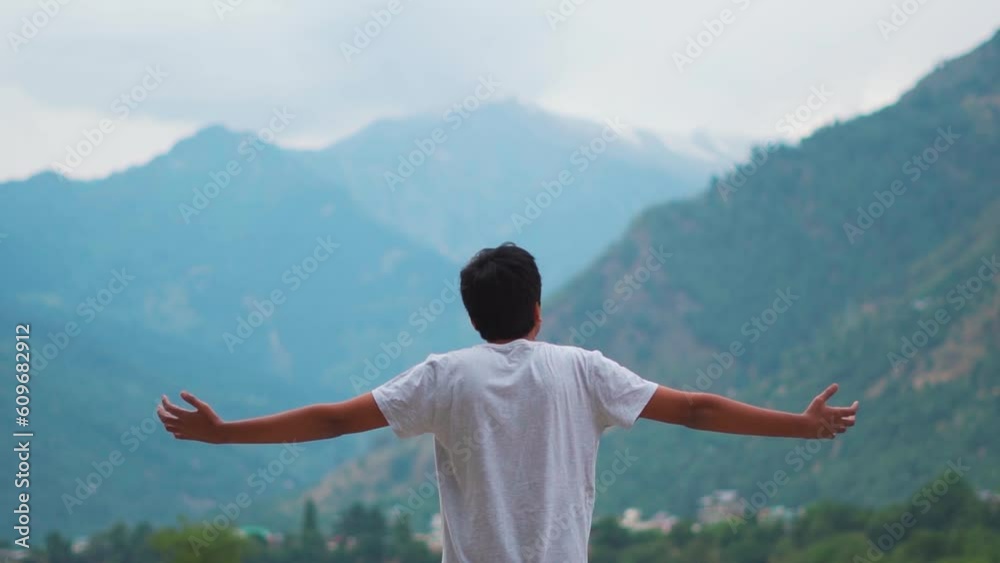 Young Indian man raised his arms while standing against beautiful ...