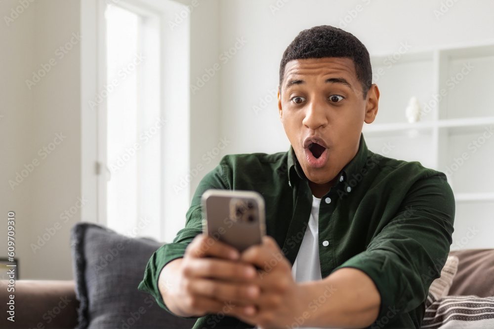 Foto de Happy excited African American man holding a mobile phone in ...