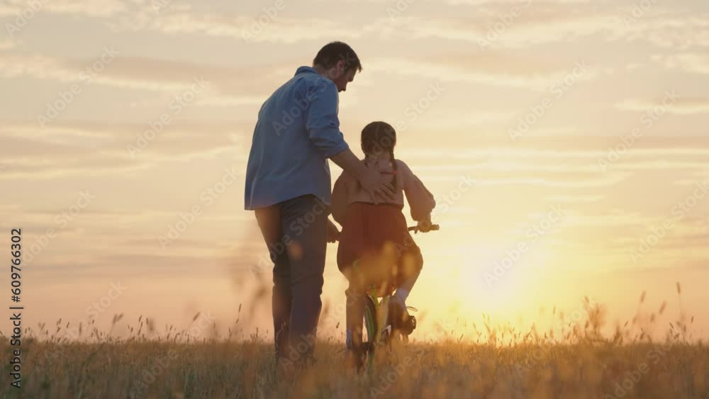 Kid Girl learns to ride bike. Happy family nature. Dad helps his ...