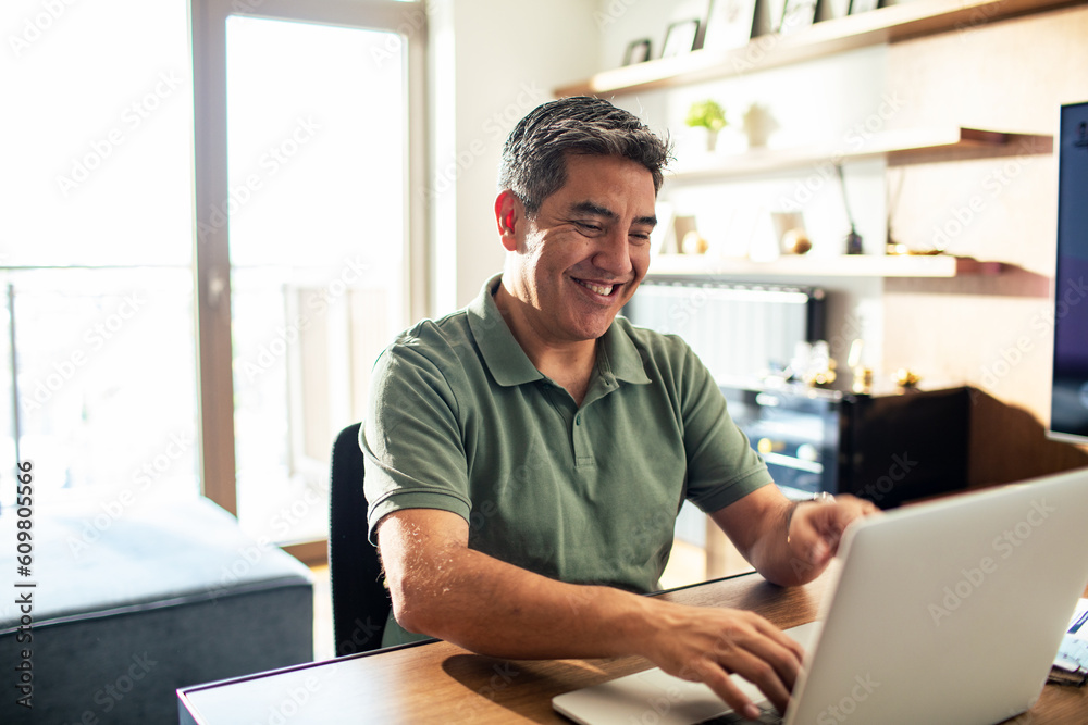 Middle aged man working on his laptop and going over his bills at home ...
