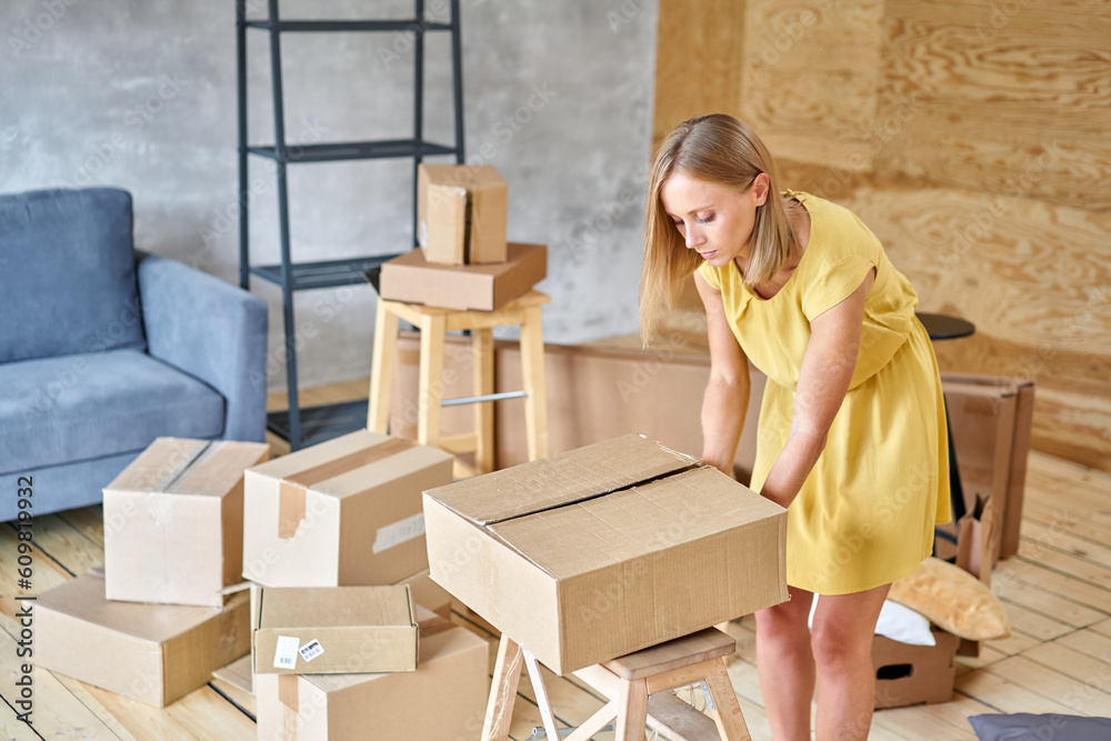 Young girl packing plates into the boxes ready to move. Woman unpacking ...