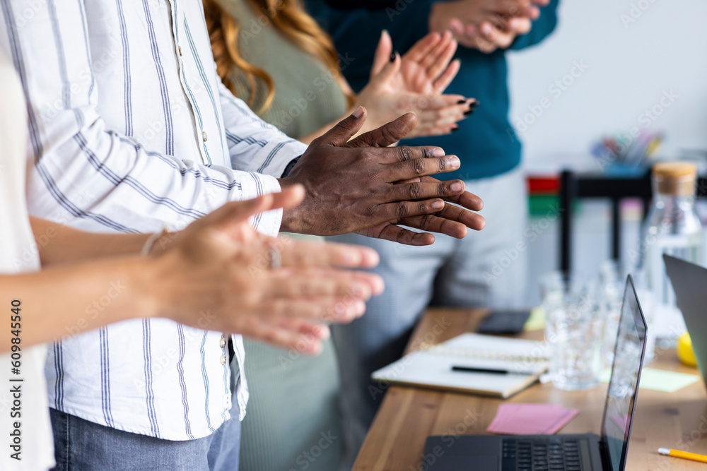 Multiracial colleagues clapping hands in front of laptop at work place ...