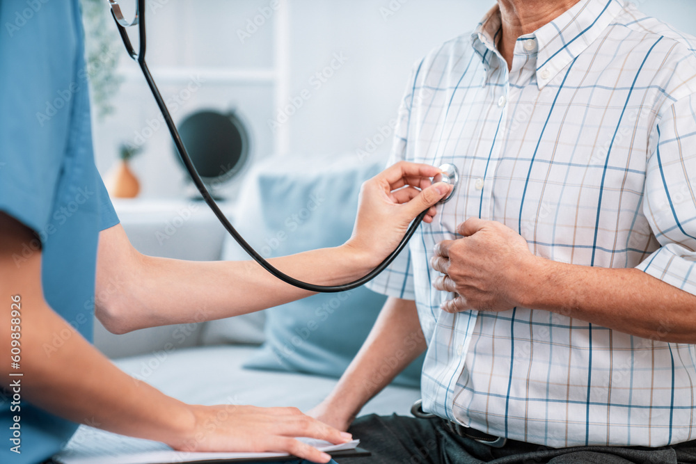 Caring young female doctor examining her contented senior patient with ...
