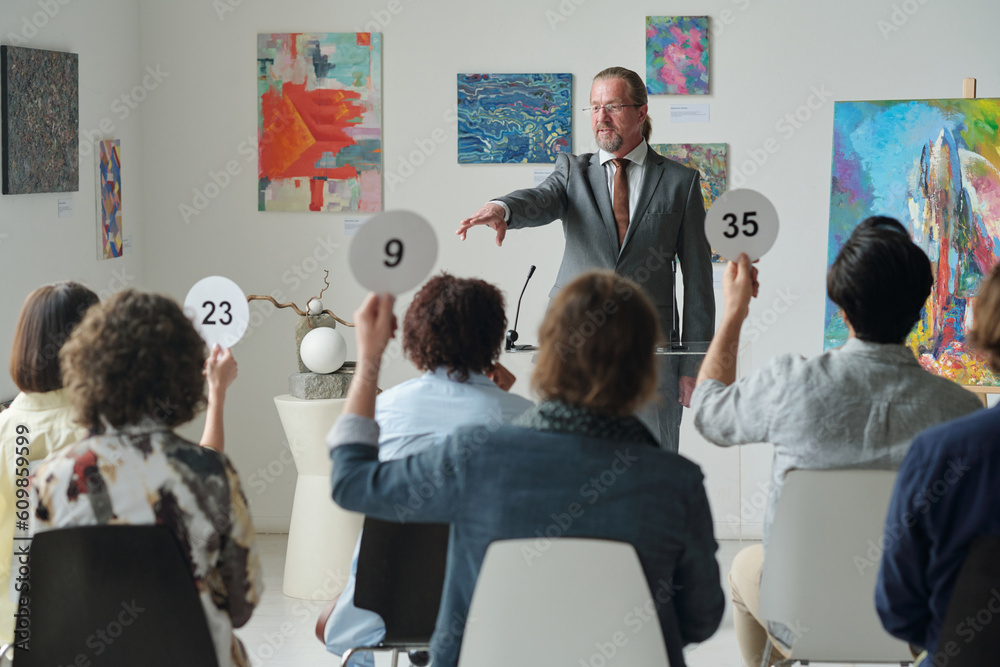 Group of people raising tablets with numbers up while sitting at ...