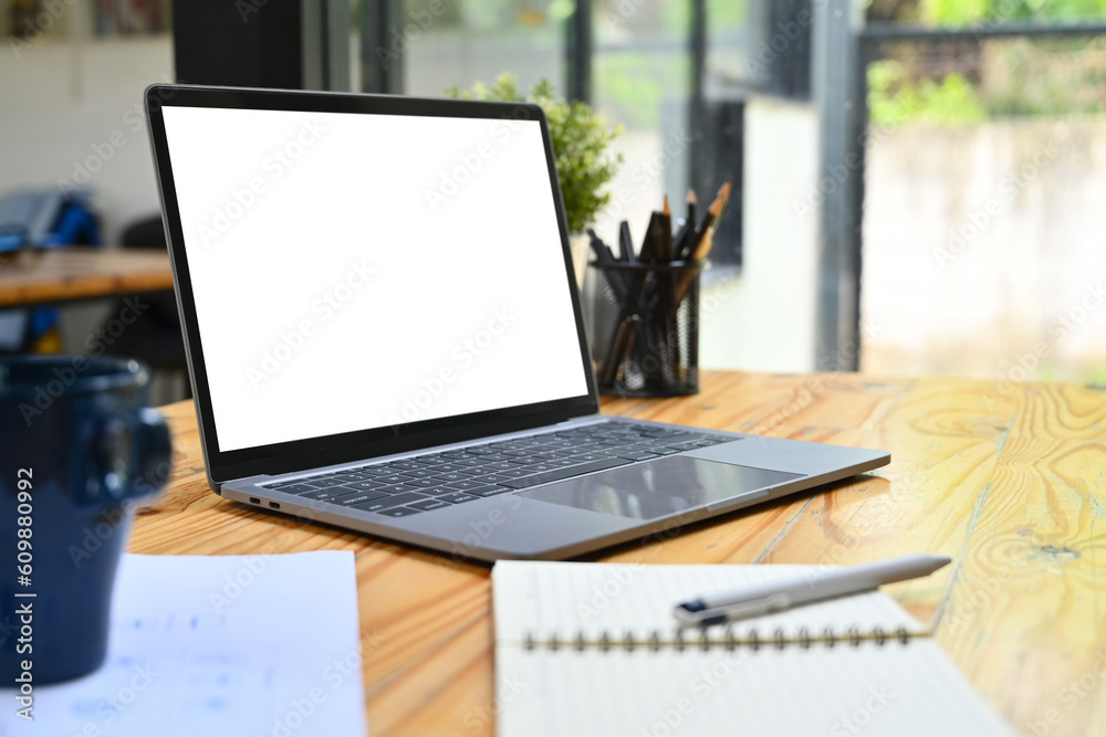 Wooden office desk with laptop computer, notepad, and cup of coffee ...