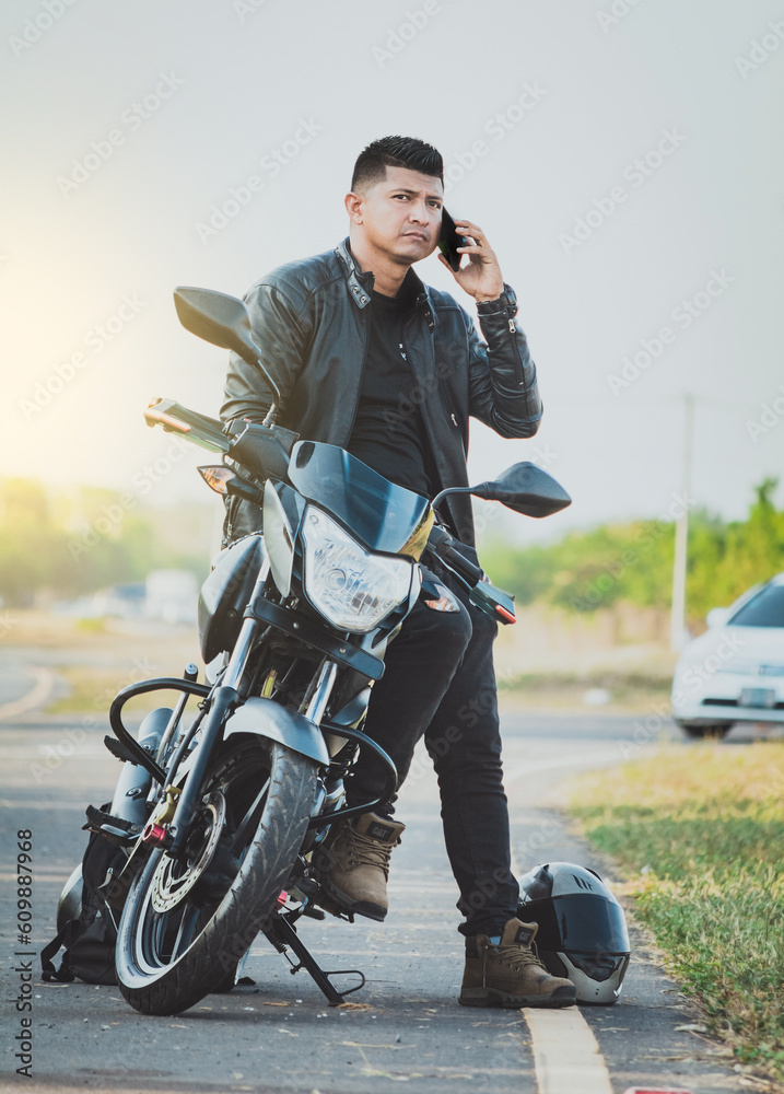 Handsome biker calling on the phone in the street. Biker sitting on ...