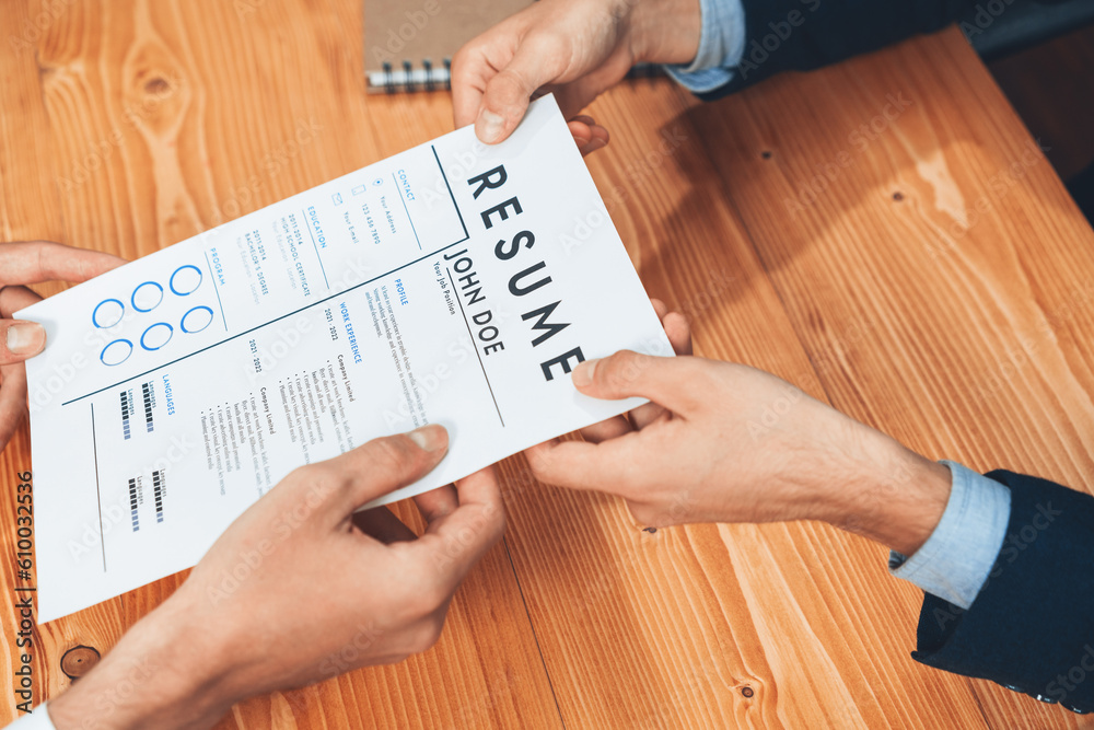 Candidate handing resume or CV over table to interviewer in corporate ...