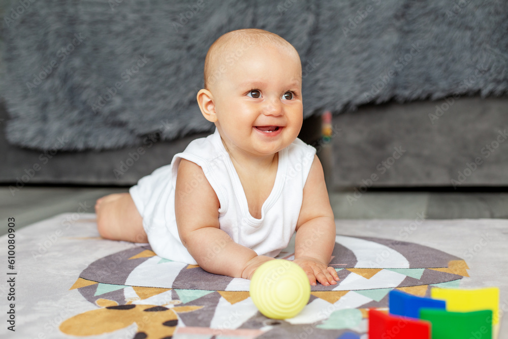 Smiling baby creep on floor of nursery grabbing colorful ball. Baby ...