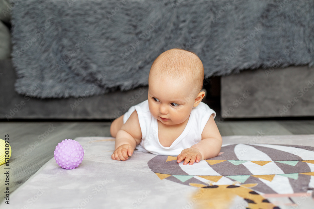 Baby creep on floor of nursery grabbing colorful ball. Baby development ...
