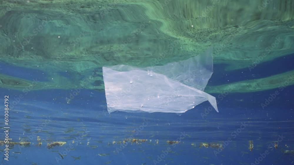 White plastic bag drifts on water surface in shallow water, slow motion ...