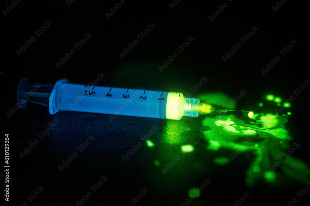 Syringe with fluorescent green ink illuminated by ultraviolet light ...