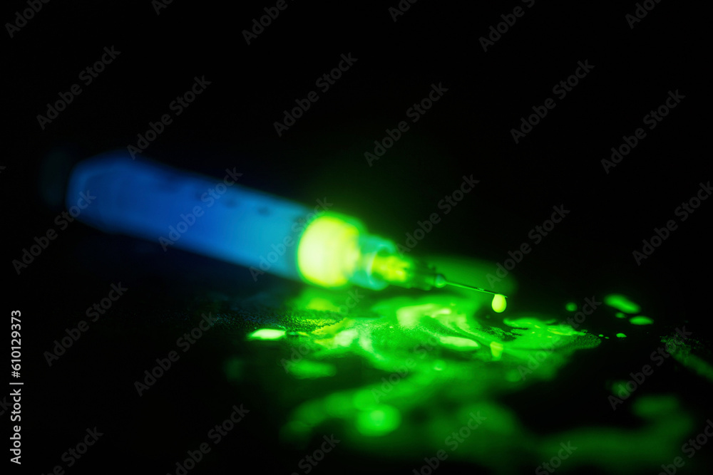 Syringe with fluorescent green ink illuminated by ultraviolet ...