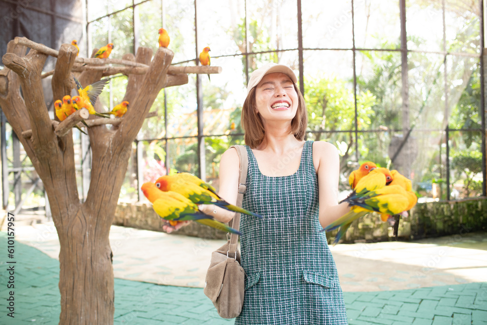 Asian beautiful woman enjoying with bird on hand and body in cage ...
