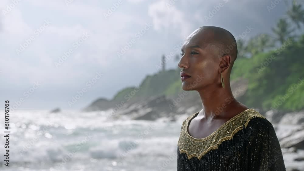LGBTQIA black person in luxury dress on stunning sea shore closeup ...