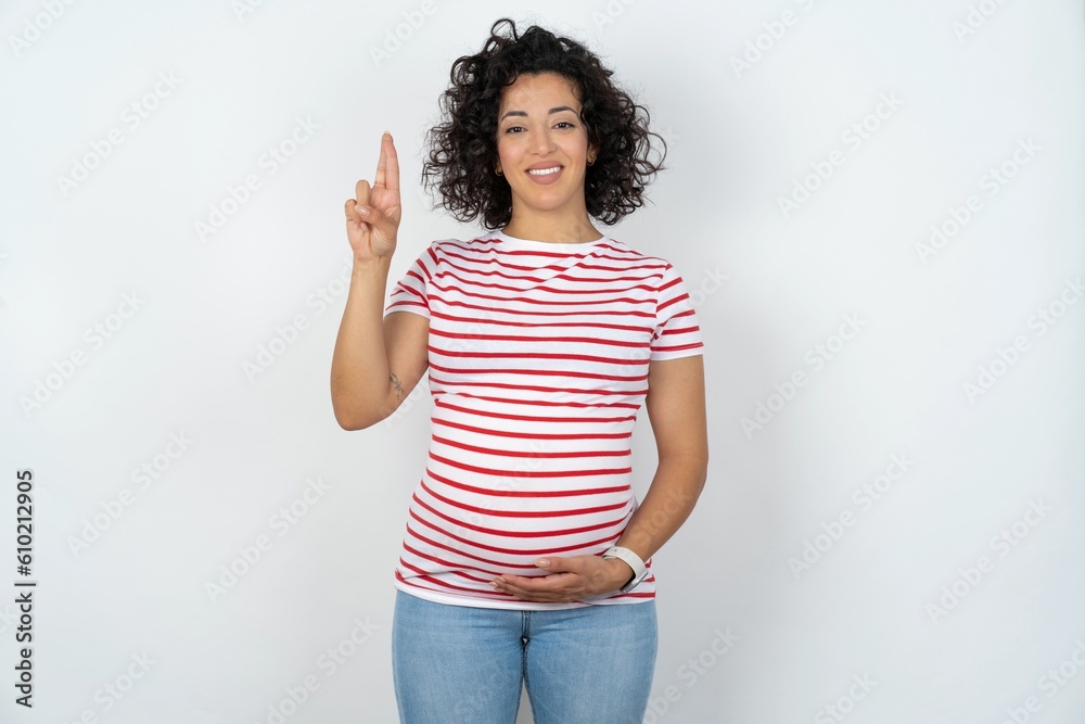 young pregnant woman wearing striped t-shirt over white background ...