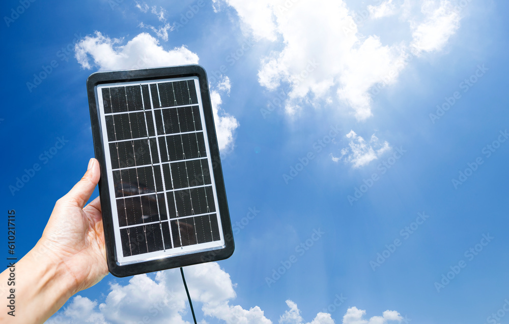 Portable solar cell panel in girl hand over sky background, green ...