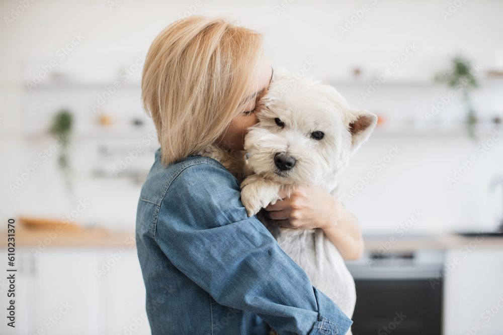 Close up view of tender young woman cuddling little white dog while ...