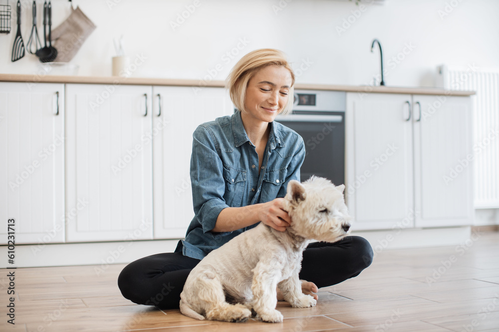 Happy caucasian female adult in casual clothes rubbing ears of small ...