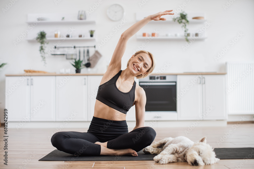 Portrait of slim woman in yoga outfit breathing in Parsva Sukhasana ...
