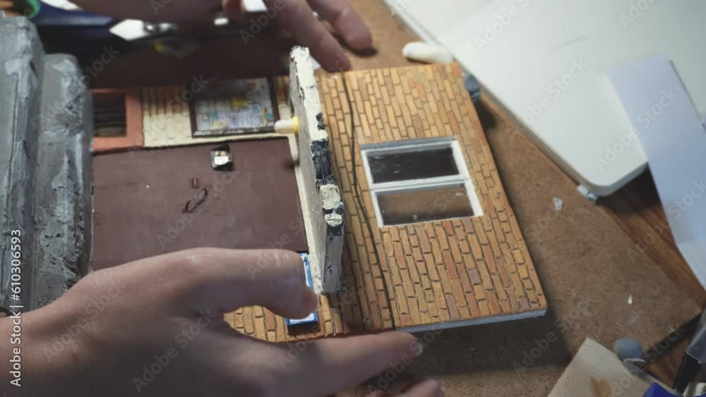 A master of miniatures showcases a small brick wall with a window, an ...