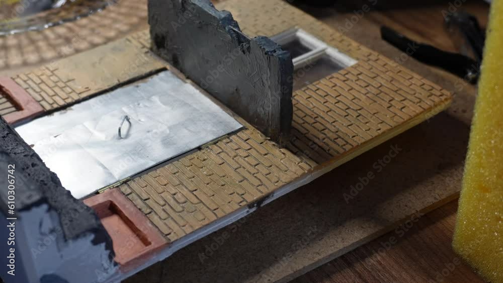 A master of miniatures showcases a small brick wall with a window, an ...