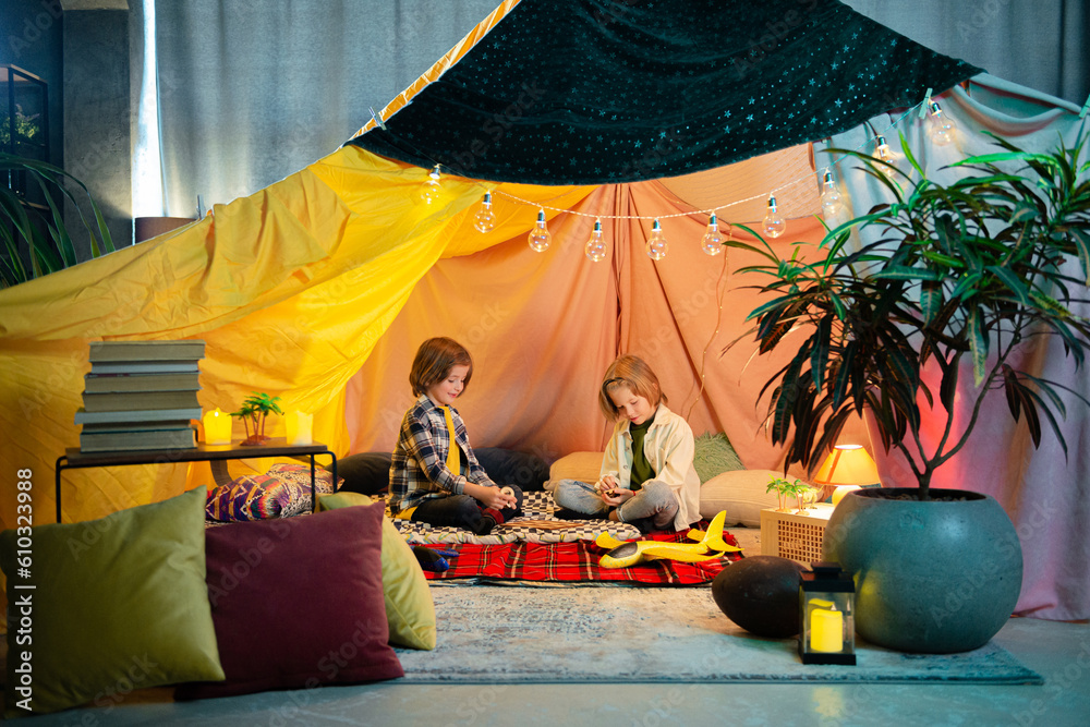 Two boys are laughing and playing together inside a big comfy tent ...