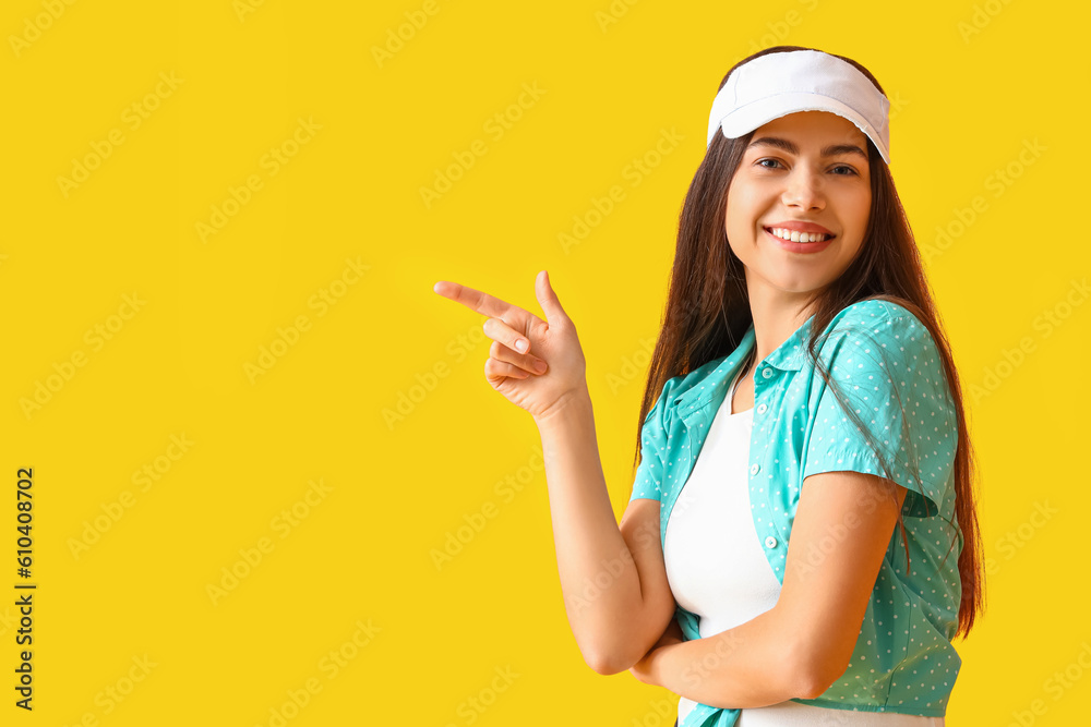 Young woman in cap pointing at something on yellow background Stock ...