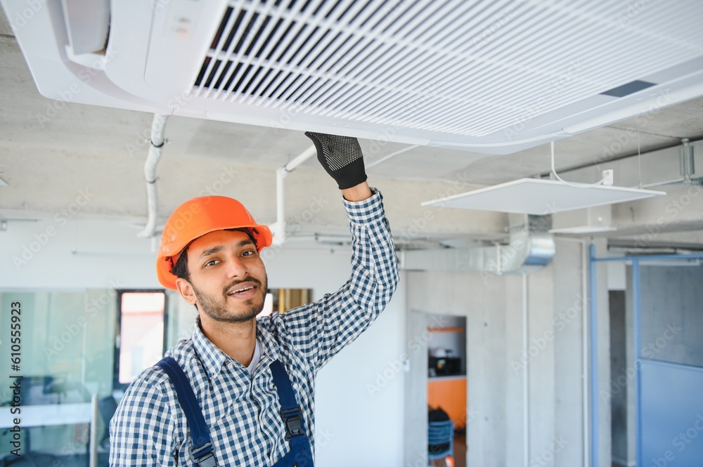Concentrated young Indian engineer setting up air conditioner. Stock ...