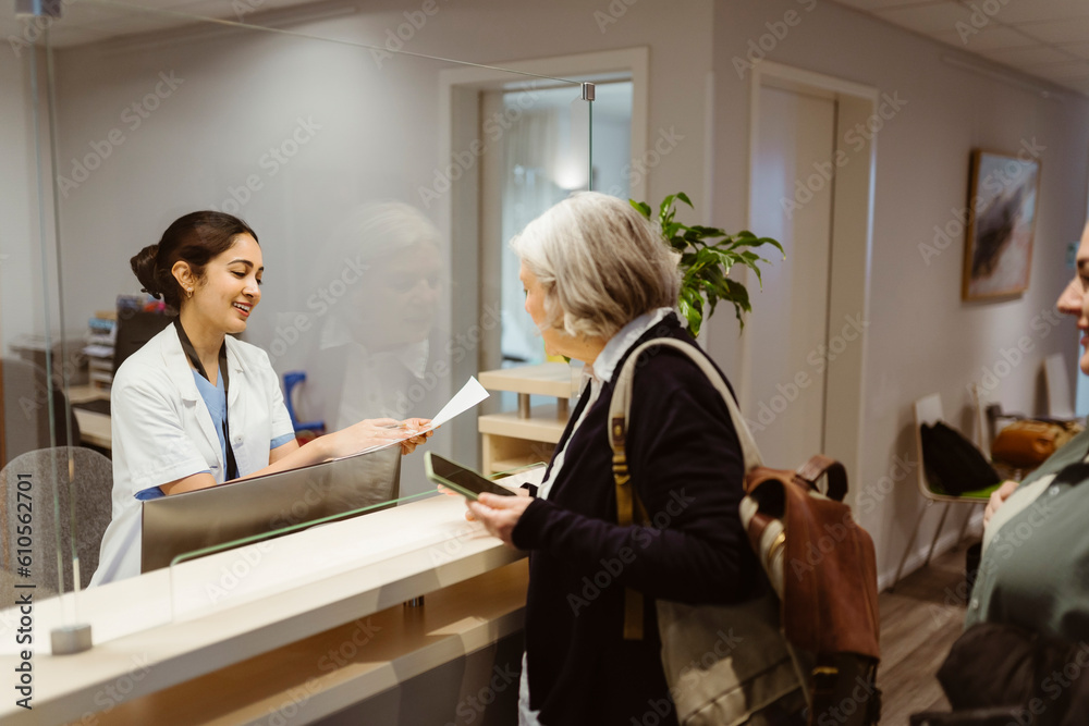 Smiling receptionist explaining form filling procedure to patient ...