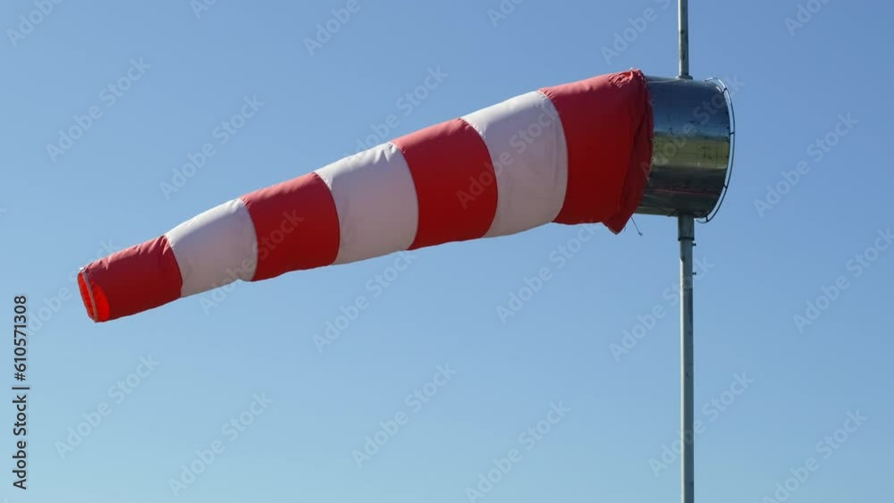 Windsock is waving in the wind against a clear blue sky. Close-up view ...