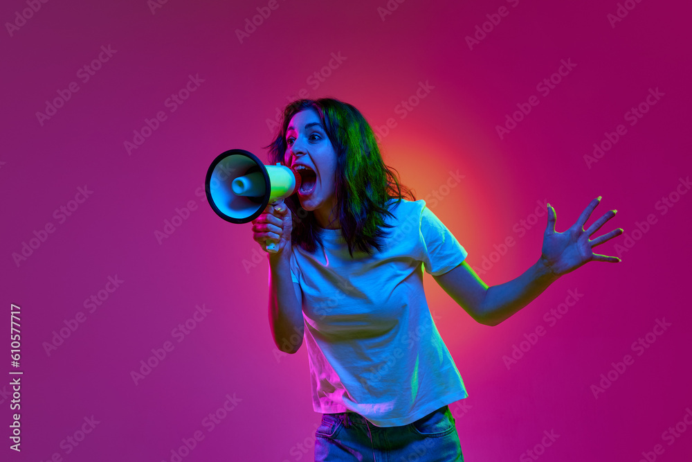 Portrait of serious young woman, girl shouting via loudspeaker over ...