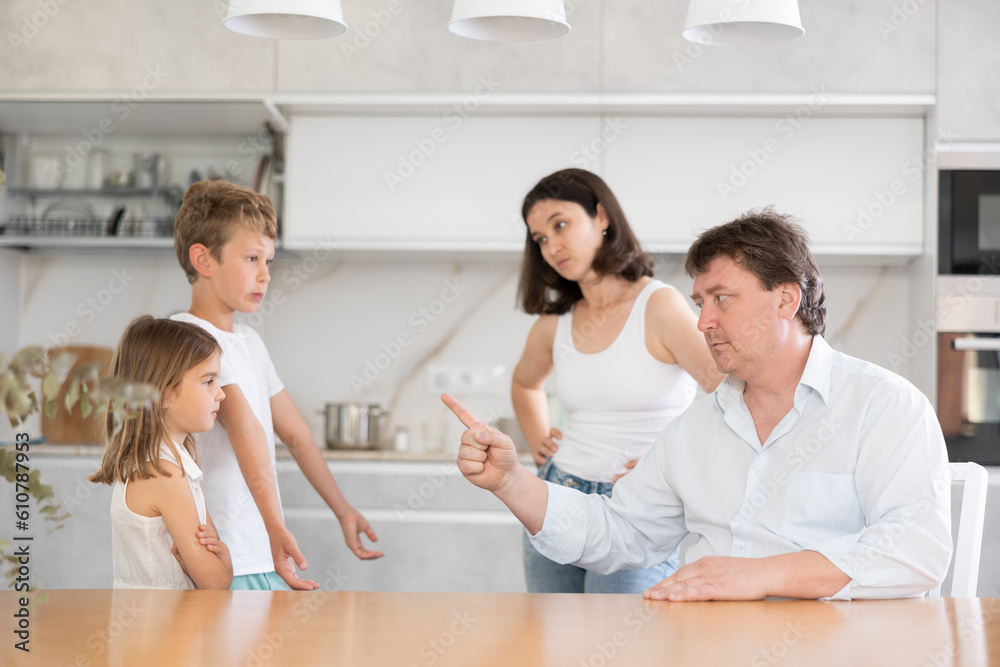 Angry parents scolding two children standing in front of them ...