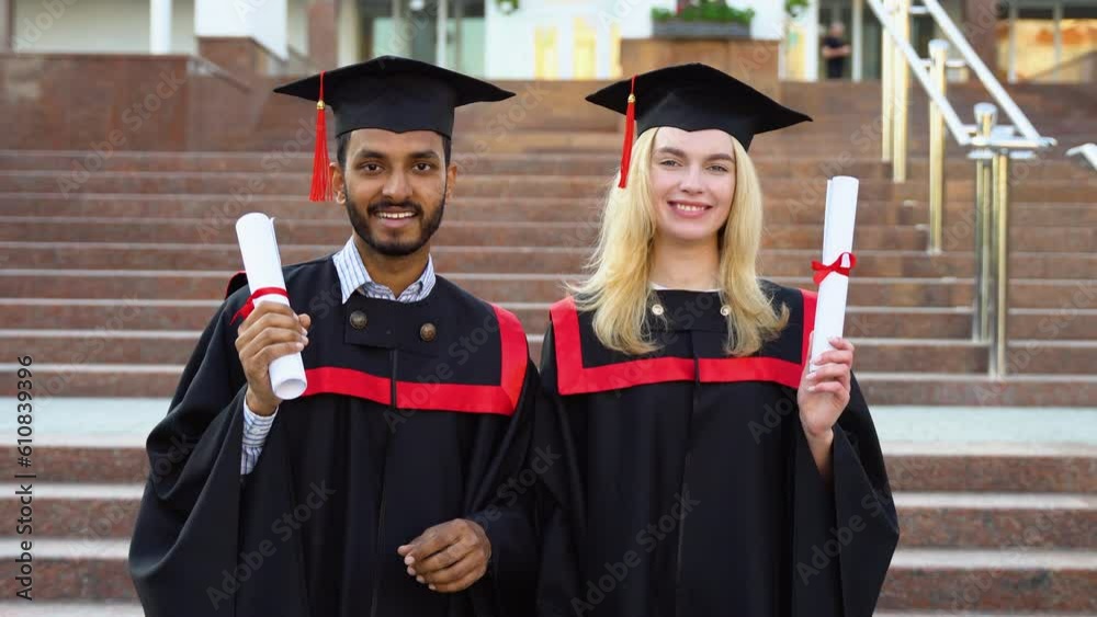 Portrait of happy multiracial graduates. Two friends in graduation caps ...