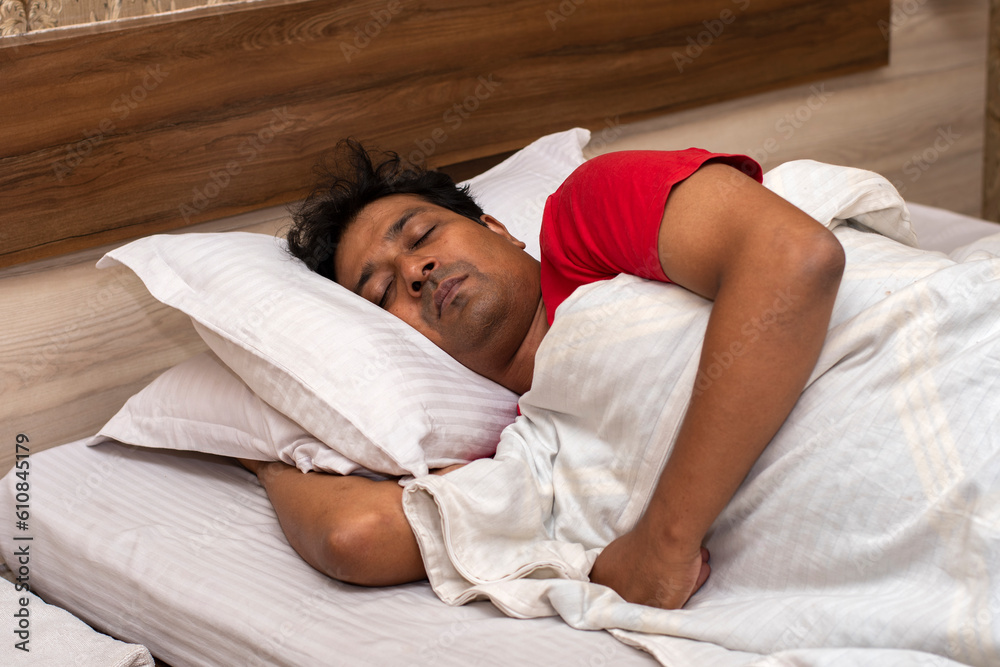 Side view of clean shaved Indian man sleeping on bed in bedroom. foto ...