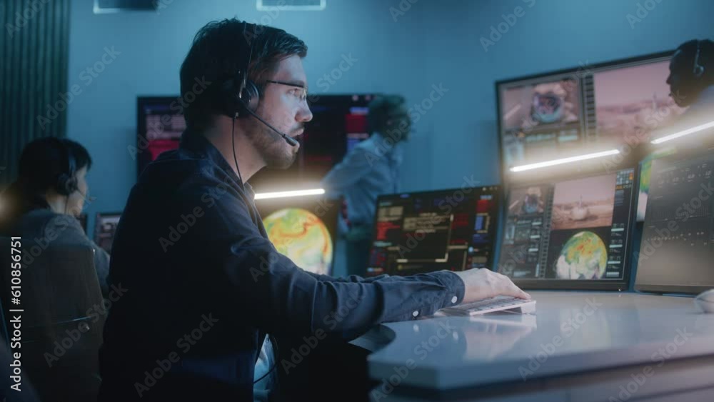 Flight control operator in headset sits in front of computers in ...