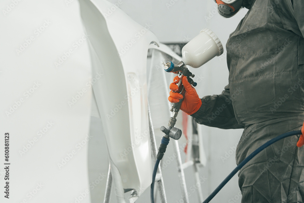 Auto painter painting a car with vaporizer gun inside a paint booth ...
