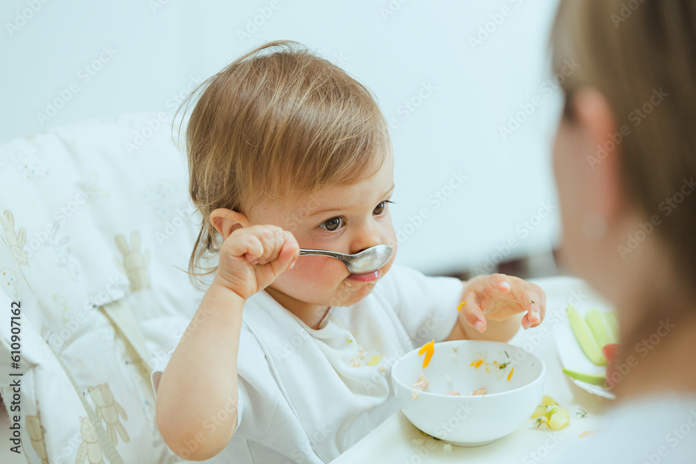 Little toddler eating using spoon in hand, learning how to feed himself ...