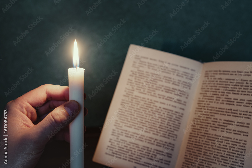 Bible reading by candlelight. A man reads a book by candlelight. Open ...