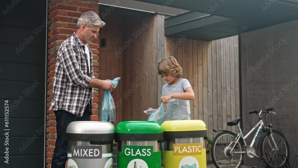 Little boy and his father throwing garbage in dustbin near home ...