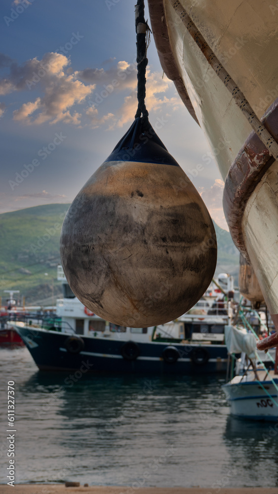 Worn fender hung on an old boat in Kalekoy harbor in Gokceada. Kalekoy ...
